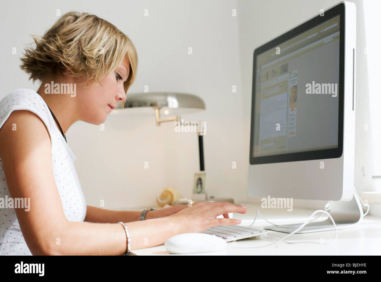 Young woman using desktop computer, side view Stock Photo - Alamy