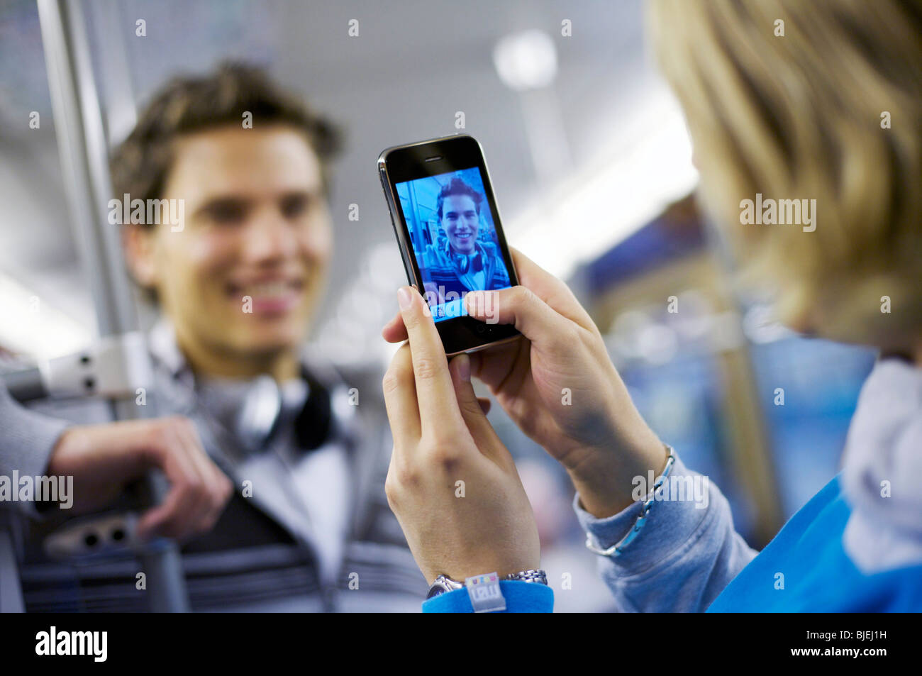 Young man in metro getting photographed with camera phone, slanted view ...