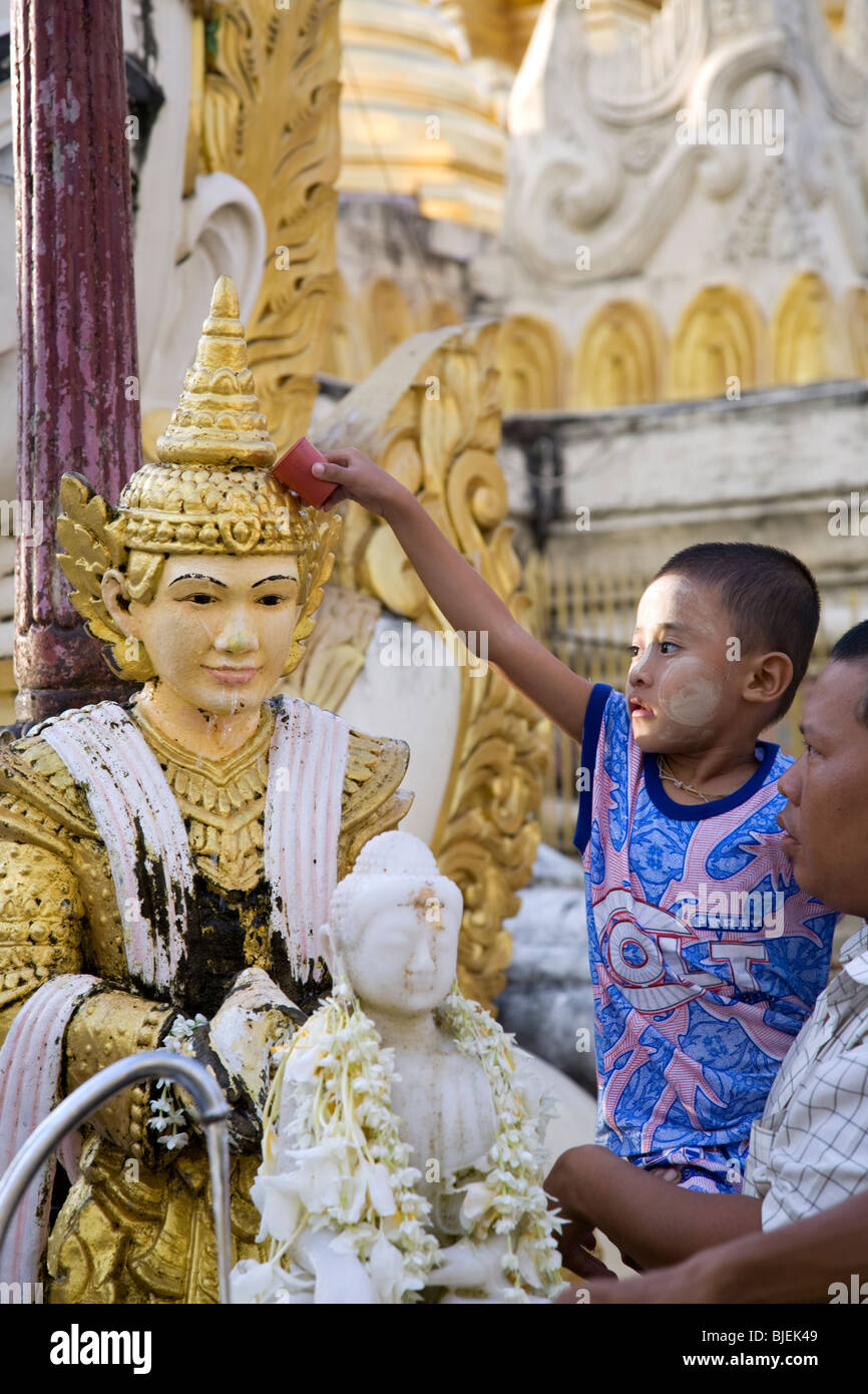Burmese boy pouring water over a Buddha statue (Theravada buddhist ...