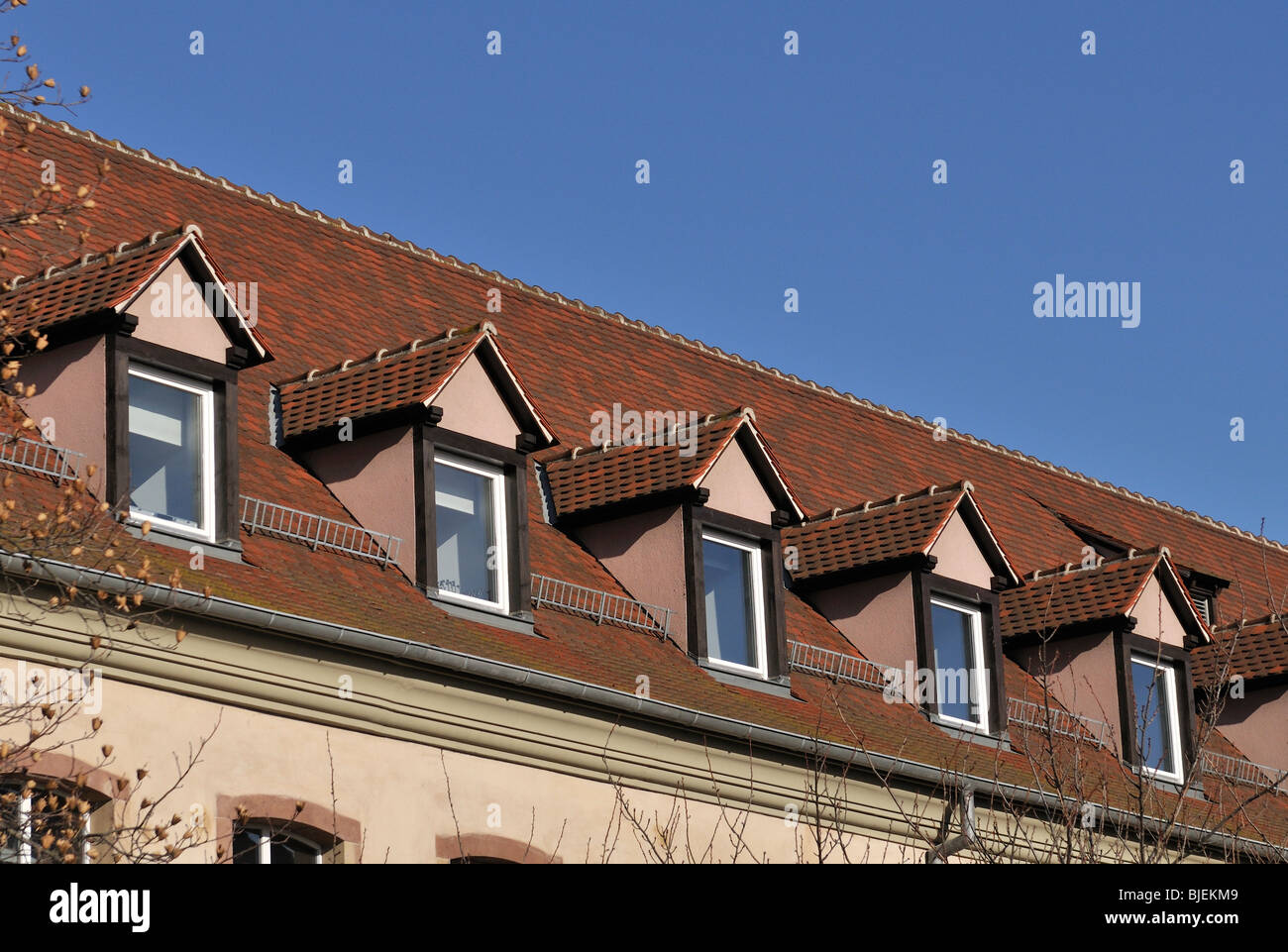 a row of top floor windows with a blue sky Stock Photo - Alamy
