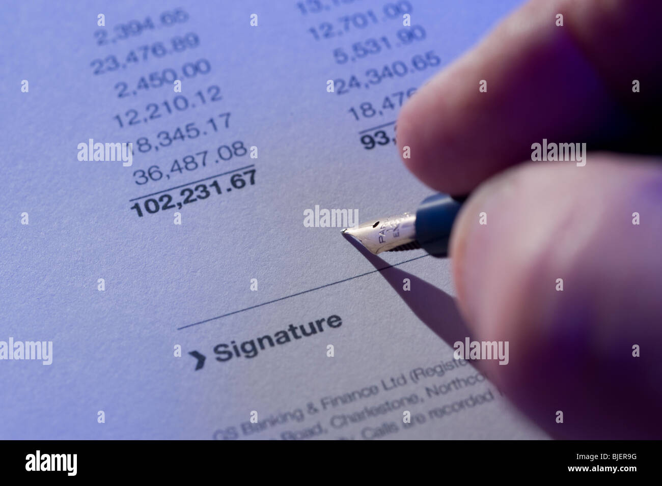 Closeup of hand with pen about to sign on a page of finance document ...