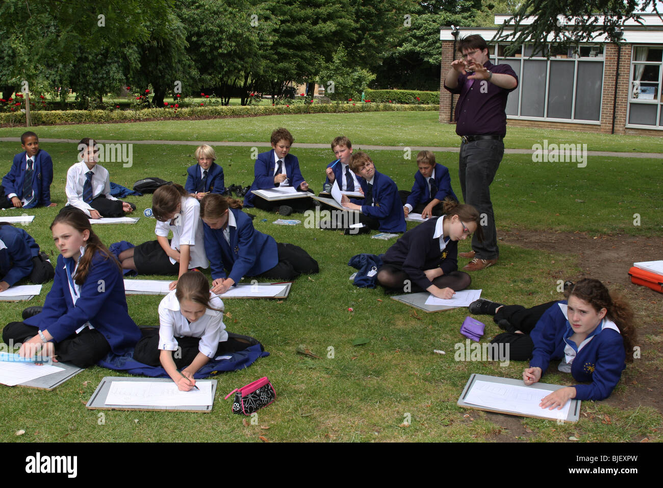 Secondary school students having art lesson on lawn of boarding school ...