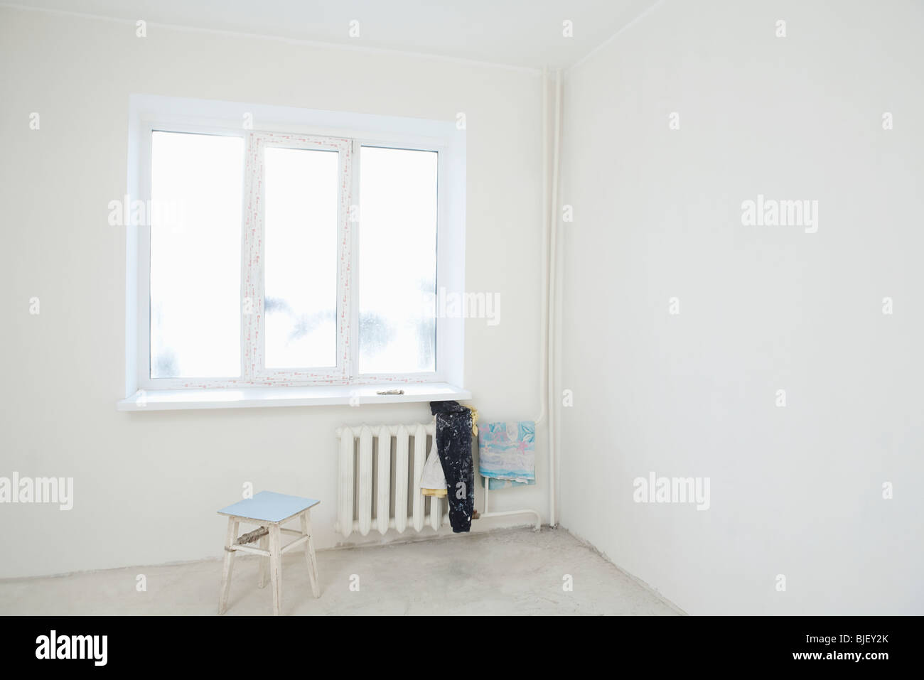 Old clothes on radiator under window of new apartment Stock Photo - Alamy