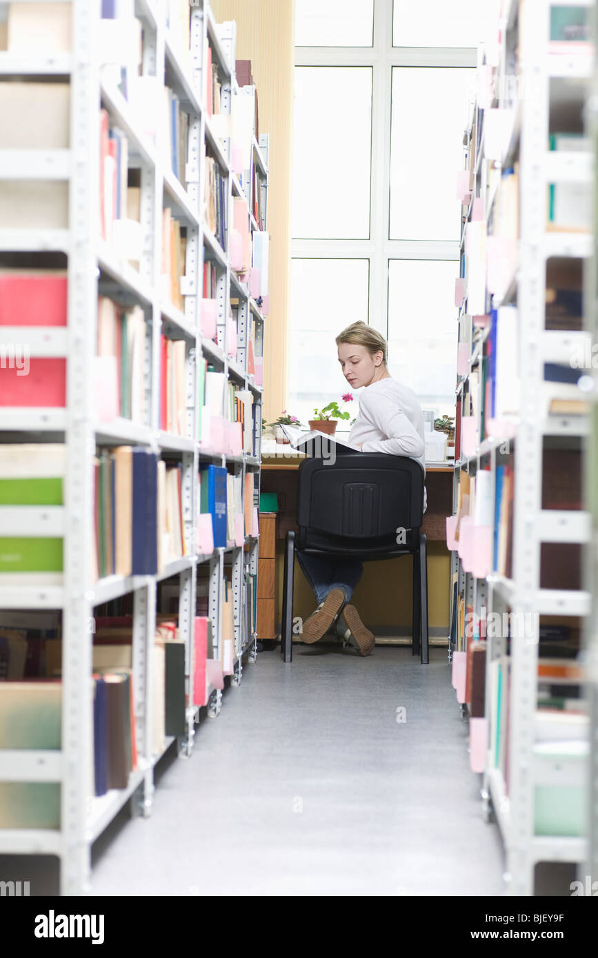 Young woman sits at desk in library Stock Photo - Alamy