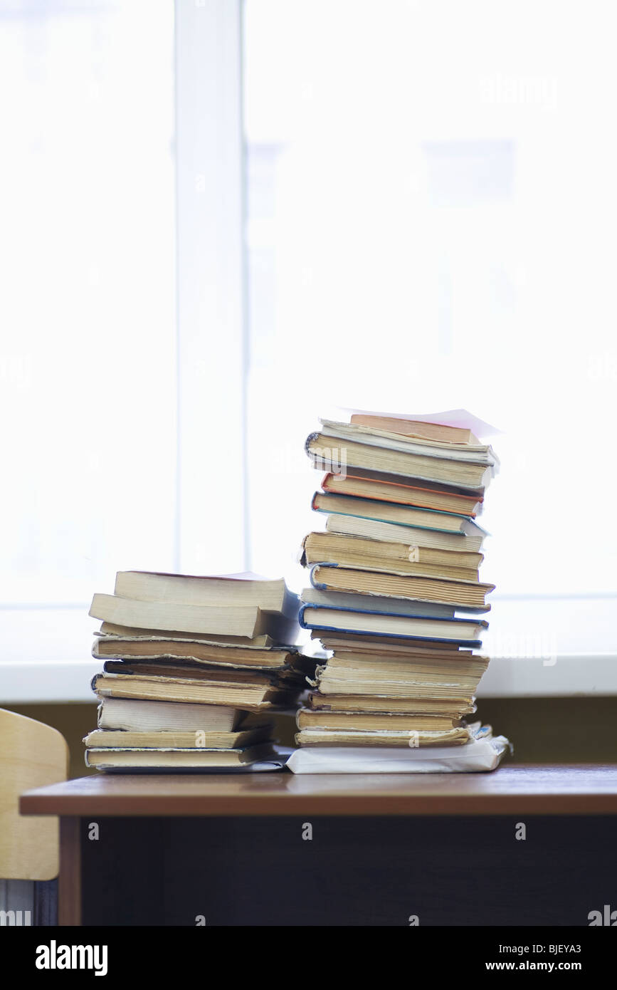 Books stacked on library table Stock Photo - Alamy