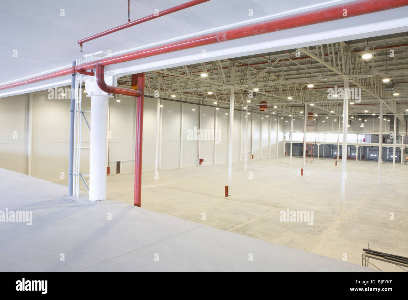 Empty warehouse with red piping Stock Photo - Alamy