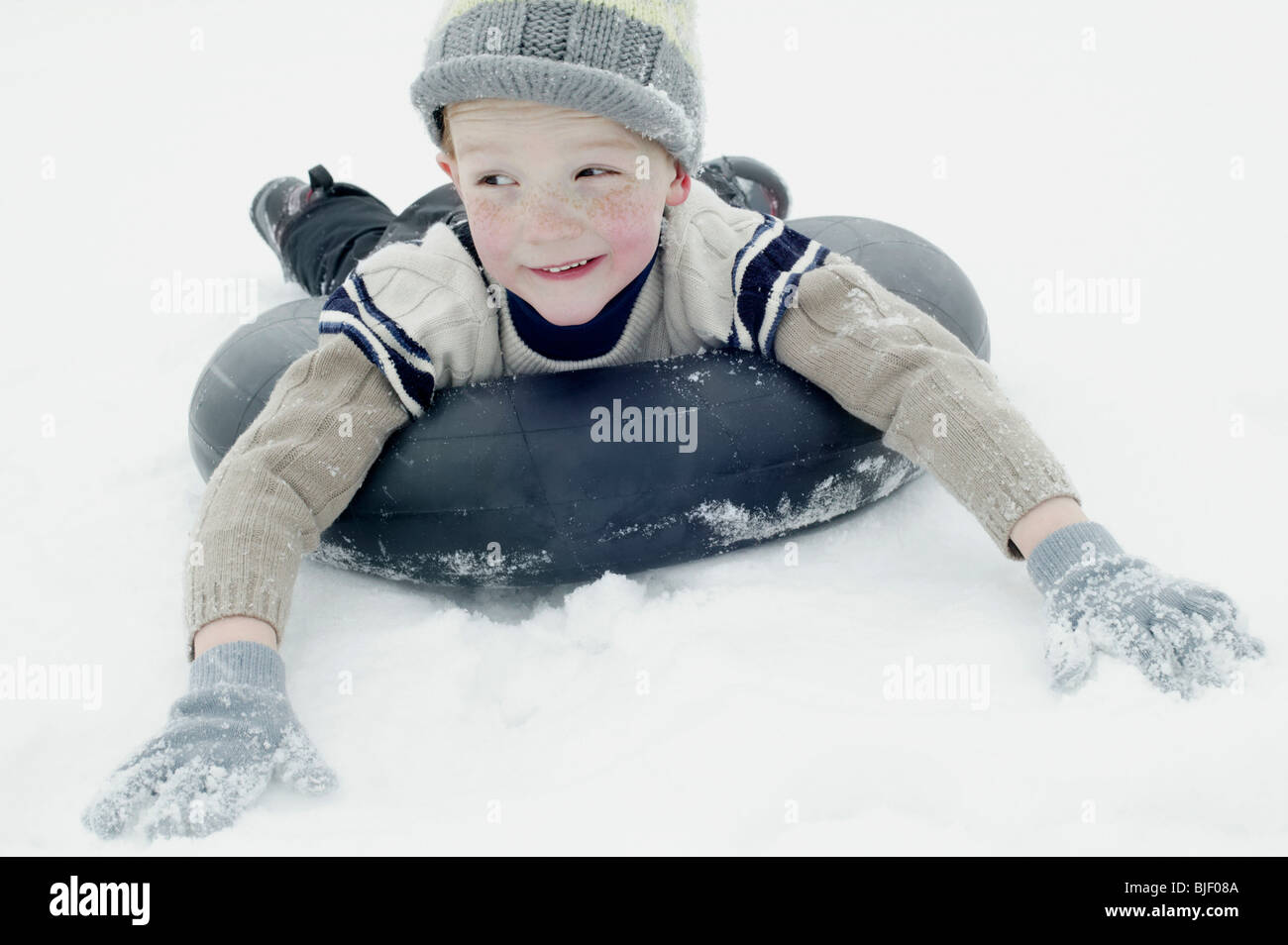 Boy in winter clothing sledging on an inner tyre Stock Photo - Alamy