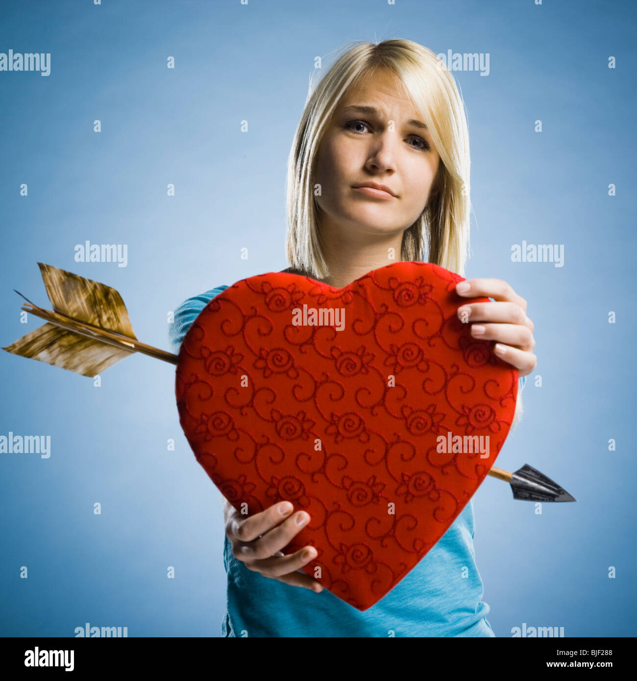woman holding up a heart with an arrow through it Stock Photo - Alamy