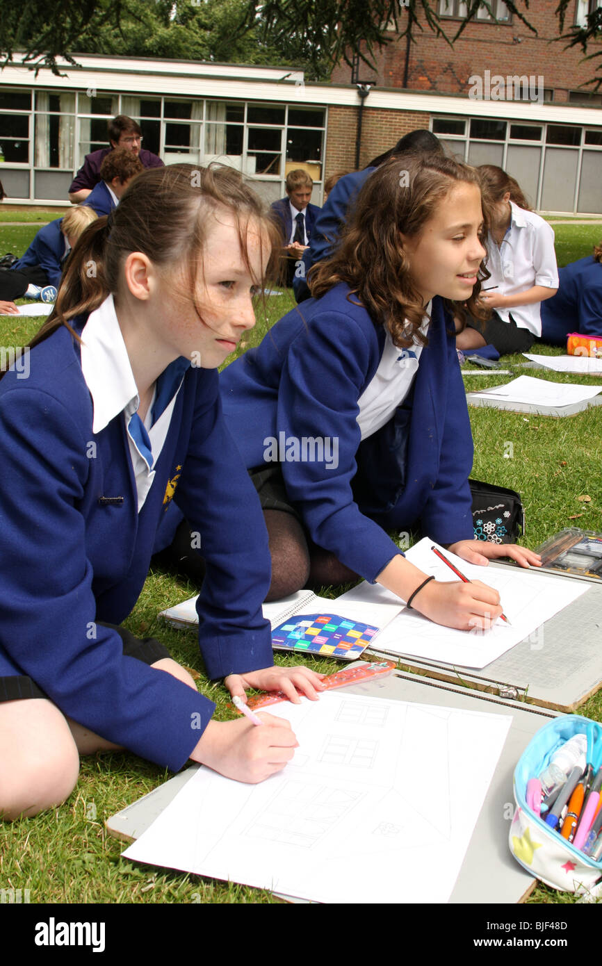 Secondary school students having art lesson on lawn of boarding school ...