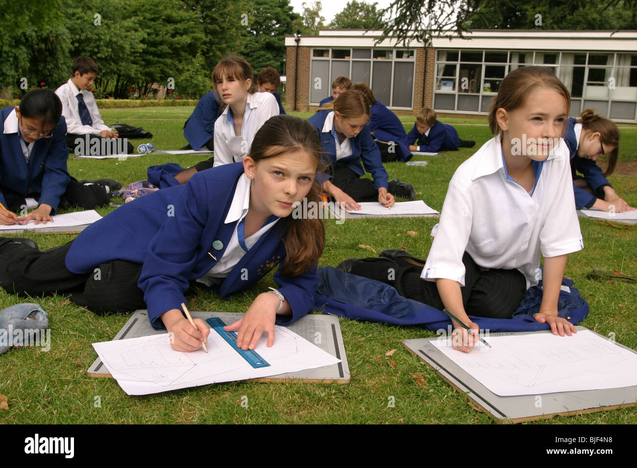 Secondary school students having art lesson on lawn of boarding school ...