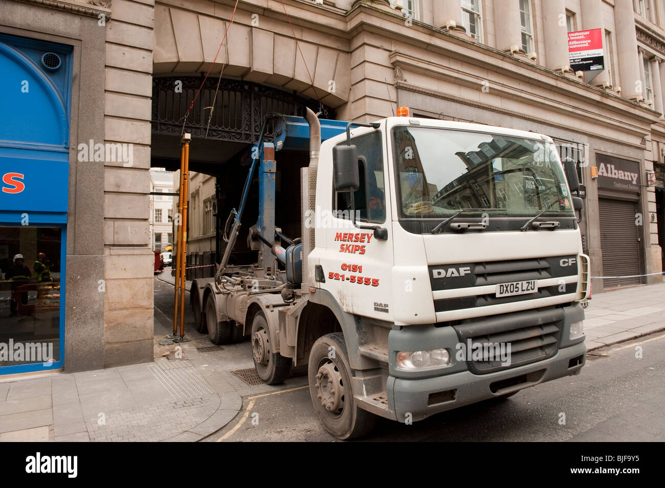 Skip lorry hiab lift stuck under archway Stock Photo - Alamy