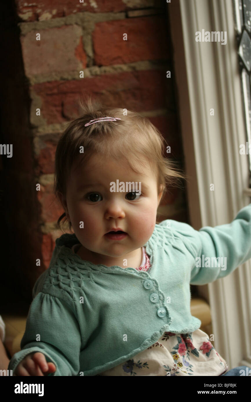 Cute little baby girl sitting by window Stock Photo - Alamy