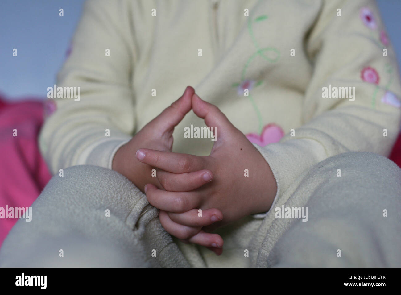 A close up of the hands of a two year old with fingers laced together ...