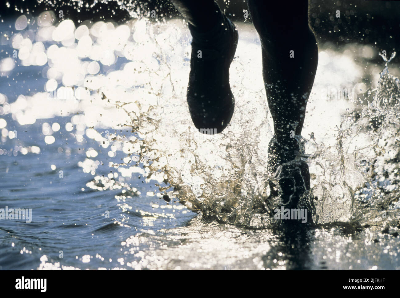 Silhouette of runner racing through water Stock Photo - Alamy