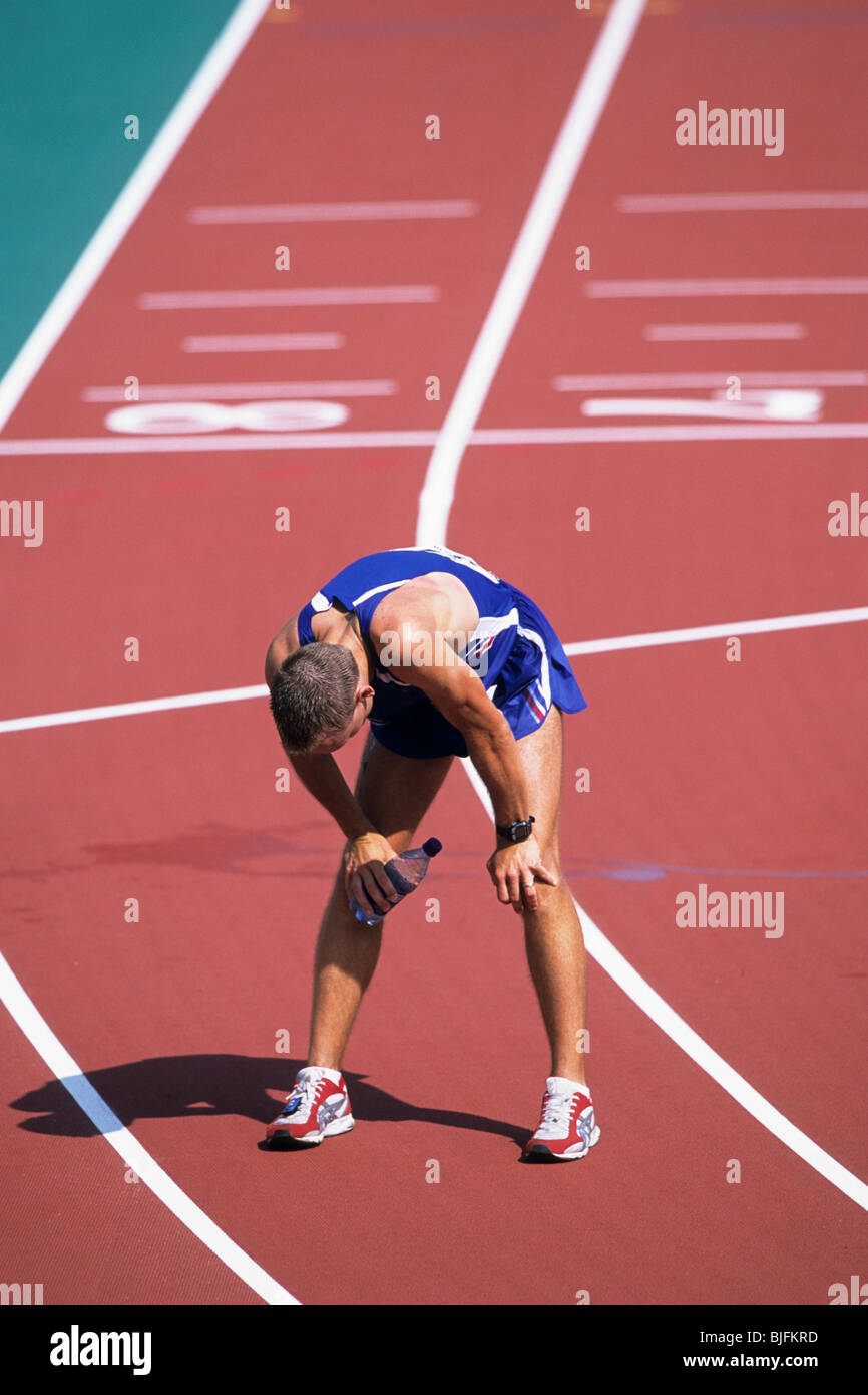 Man stands bent over on race track Stock Photo - Alamy