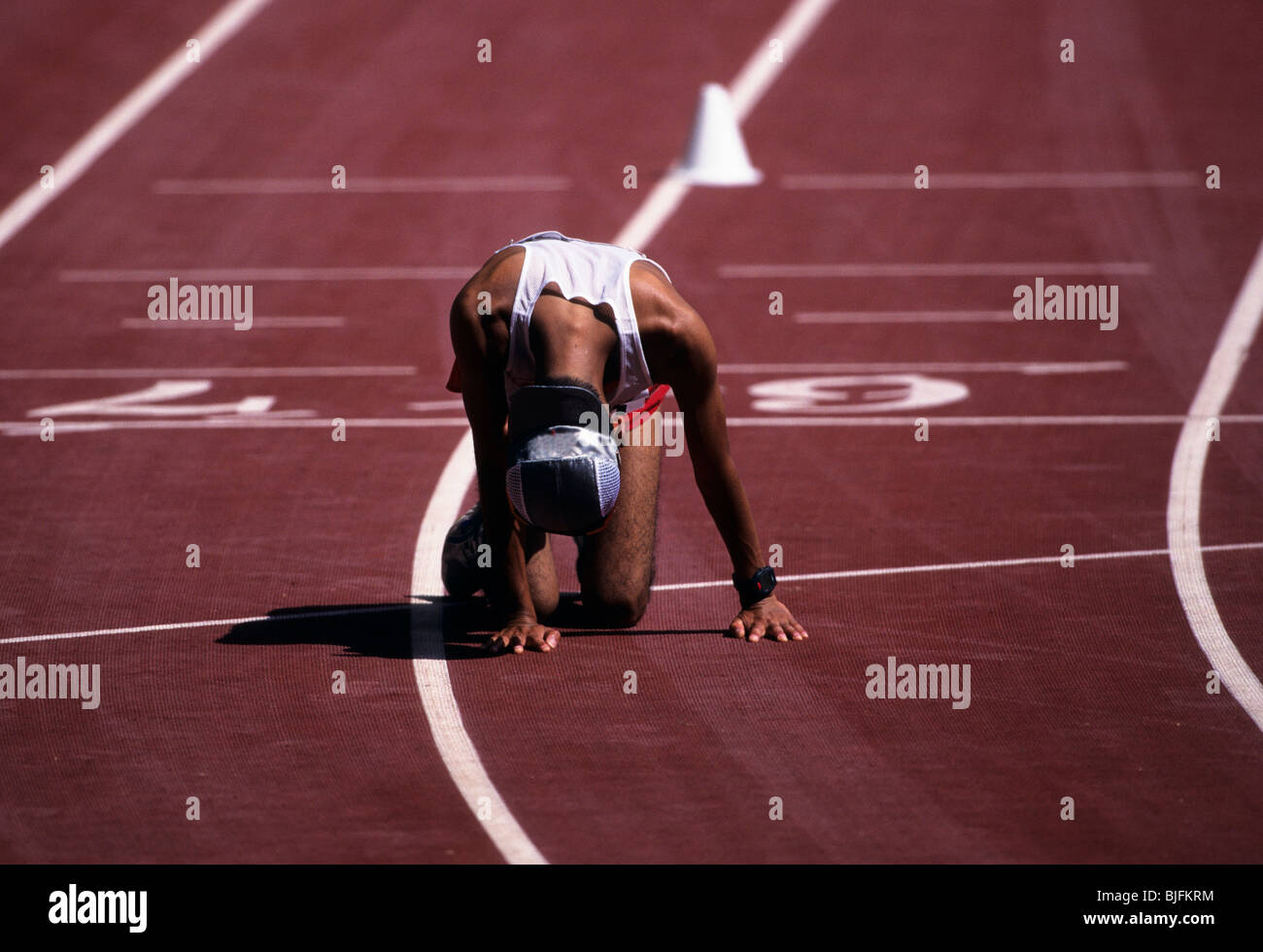 Runner kneeling on the race track Stock Photo - Alamy