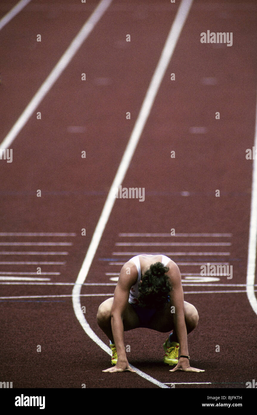 Woman kneeling on race track after a race Stock Photo - Alamy