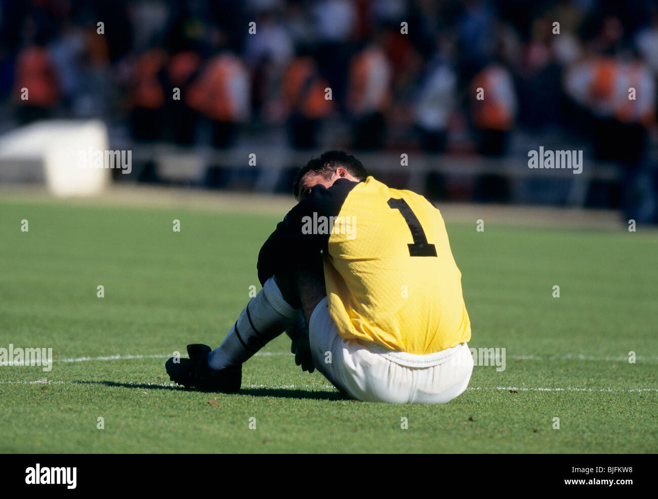 Disappointed goalkeeper sitting on the pitch Stock Photo - Alamy