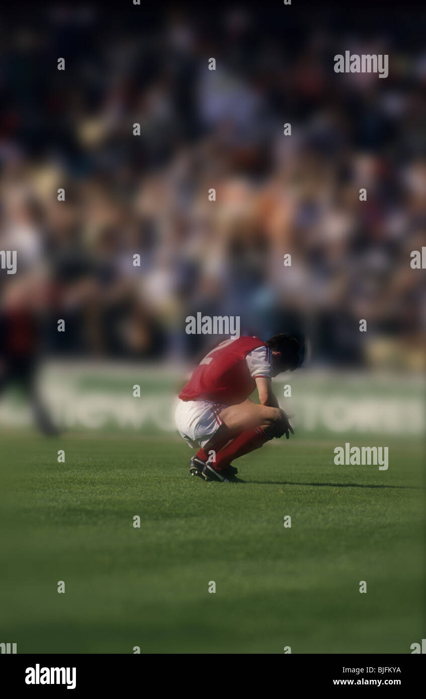 Disappointed player bent down on the pitch Stock Photo - Alamy