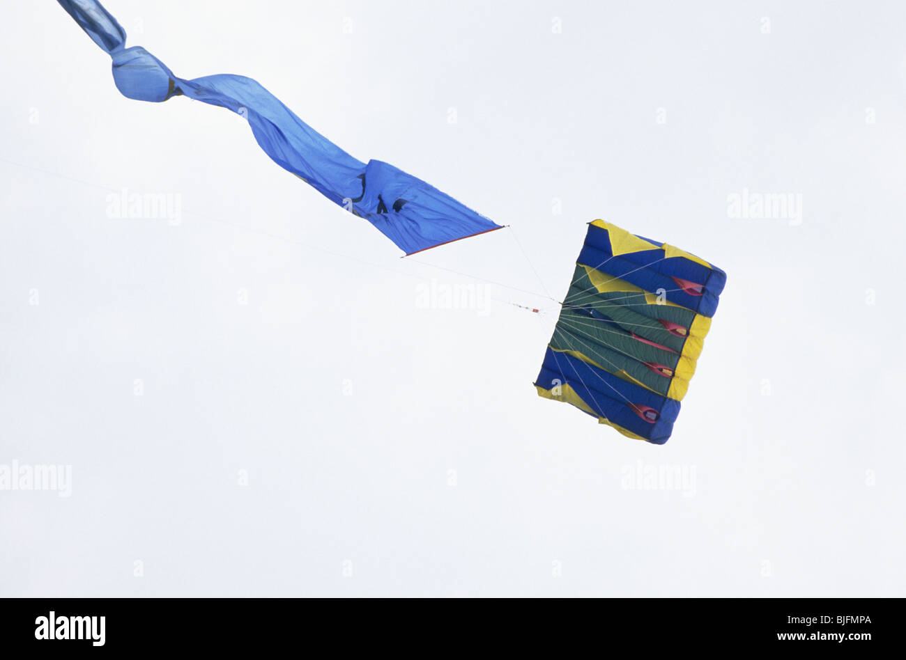 Blue and yellow Kite flying high in sky with trailing tail Stock Photo ...
