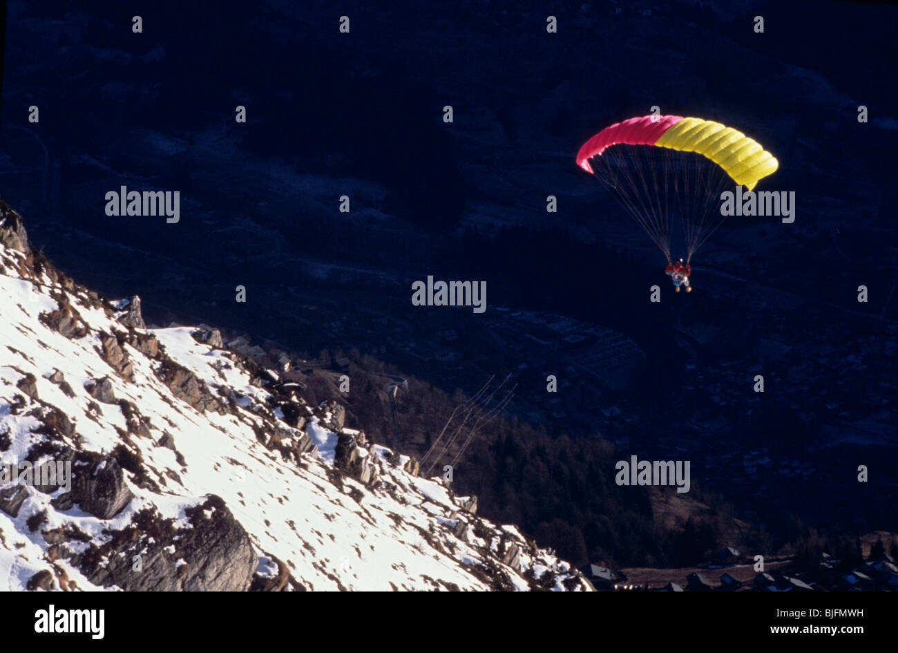 Paragliding over snow topped mountains Stock Photo - Alamy
