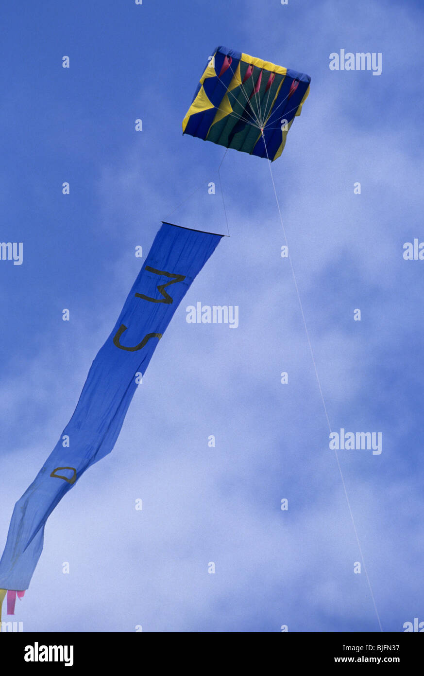 Blue and yellow Kite flying high in sky with trailing tail Stock Photo ...