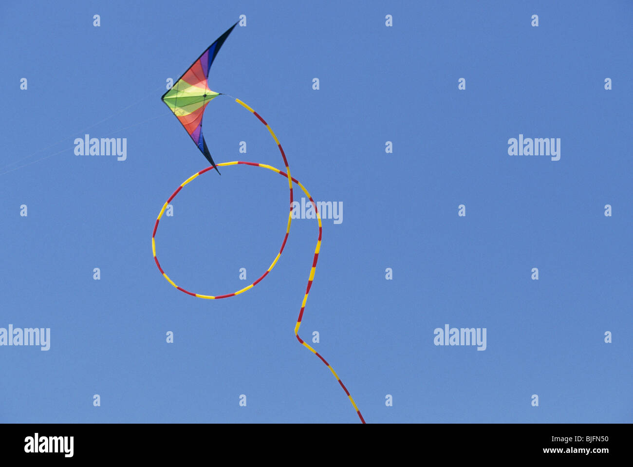 Colourful kite flying high in sky Stock Photo - Alamy