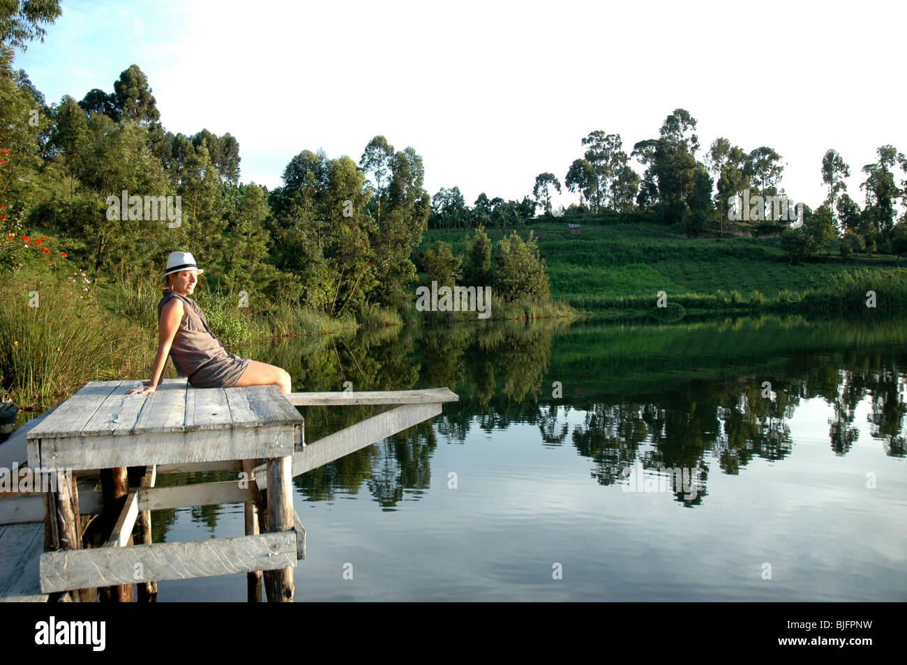 A woman sits on the jetty overlooking Lake Bunyoni. Uganda, Africa ...