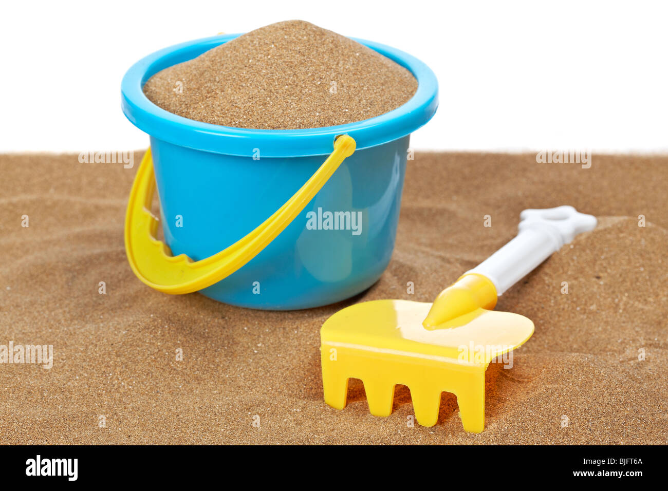 Bucket full and rake on the sand with copy space on a white background ...