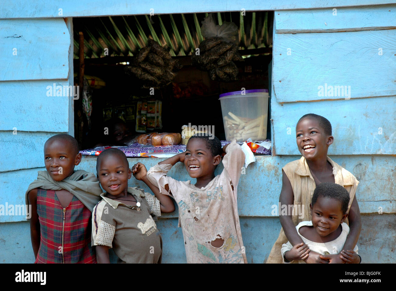 Children smile and laugh whilst standing outside the local village shop ...