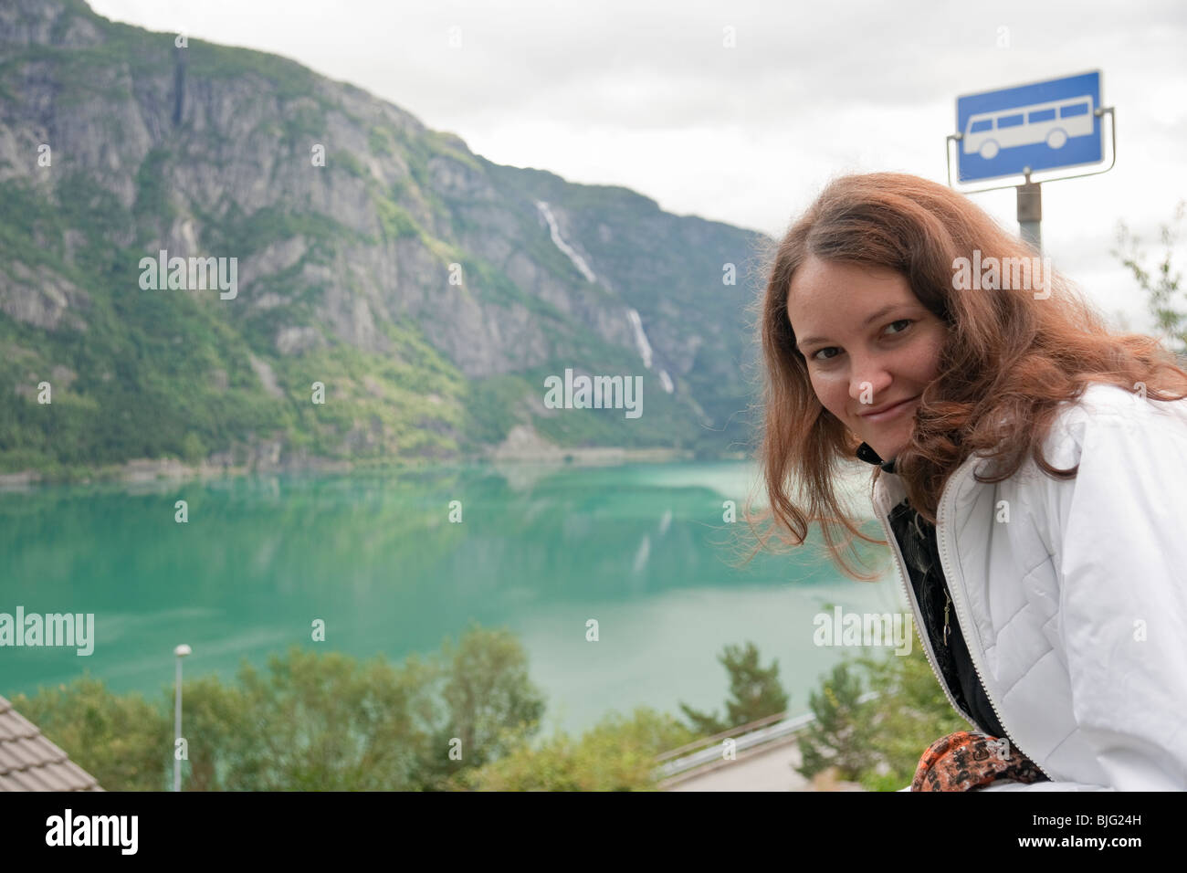 The nice girl waits for the bus at a bus stop. Norway, near to city ...