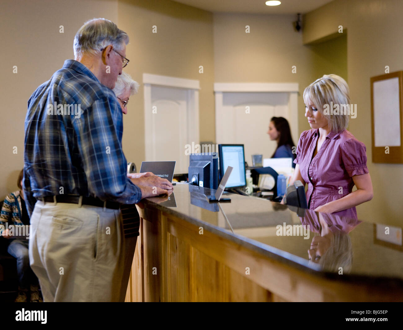 receptionist talking to patients at a doctor's office Stock Photo - Alamy