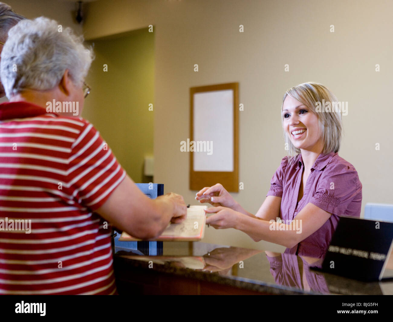 receptionist talking to patients at a doctor's office Stock Photo - Alamy