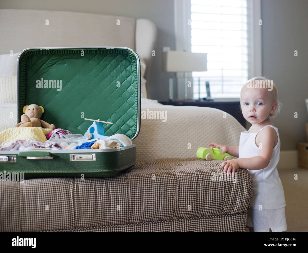 baby girl standing next to open suitcase Stock Photo - Alamy
