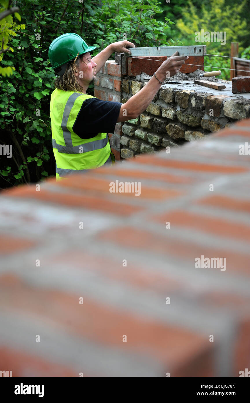 Using a spirit level during the building of a garden wall with cotswold ...