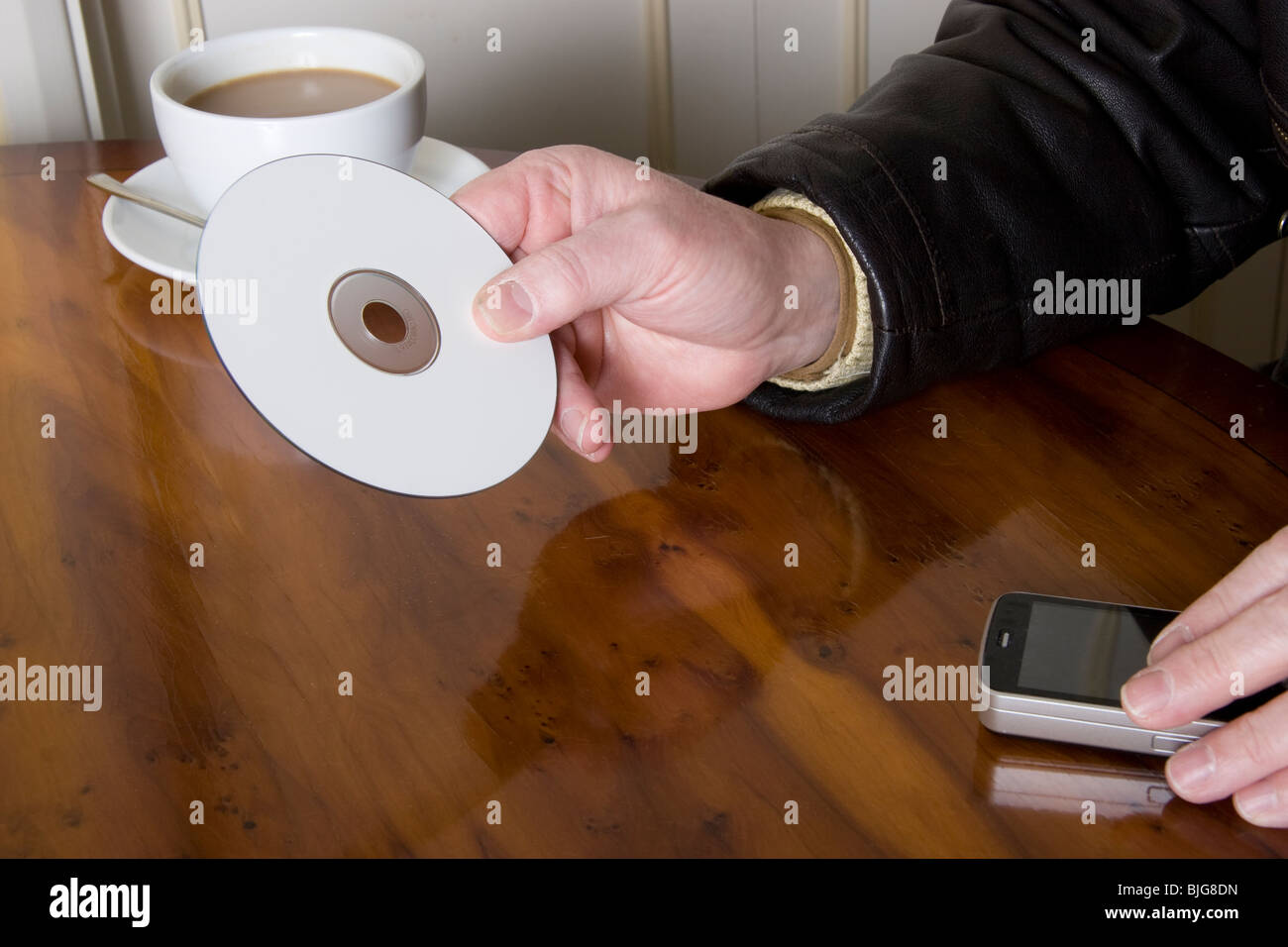 Person passing CD across a table Stock Photo - Alamy