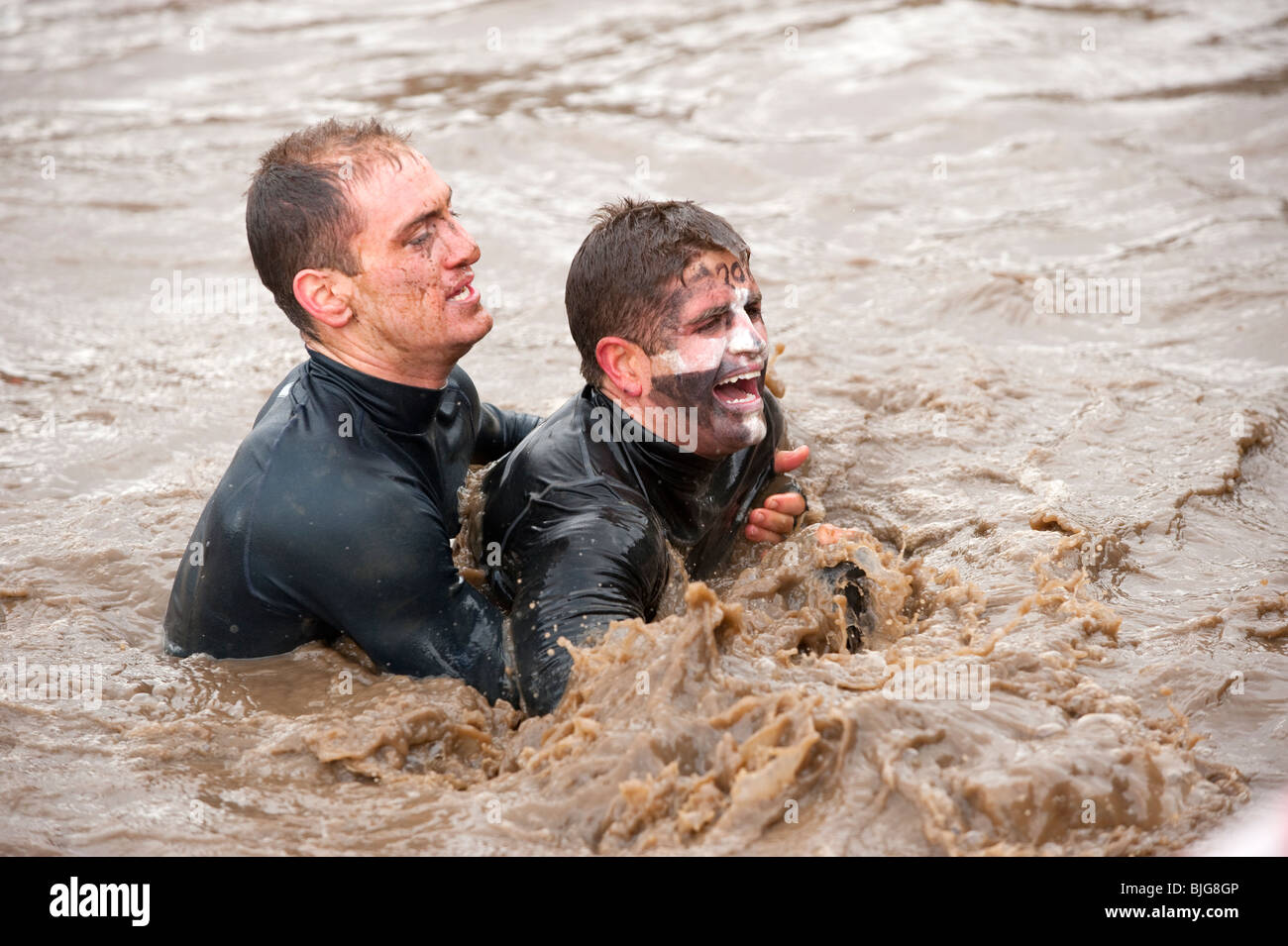 two men in deep muddy water struggling Stock Photo - Alamy