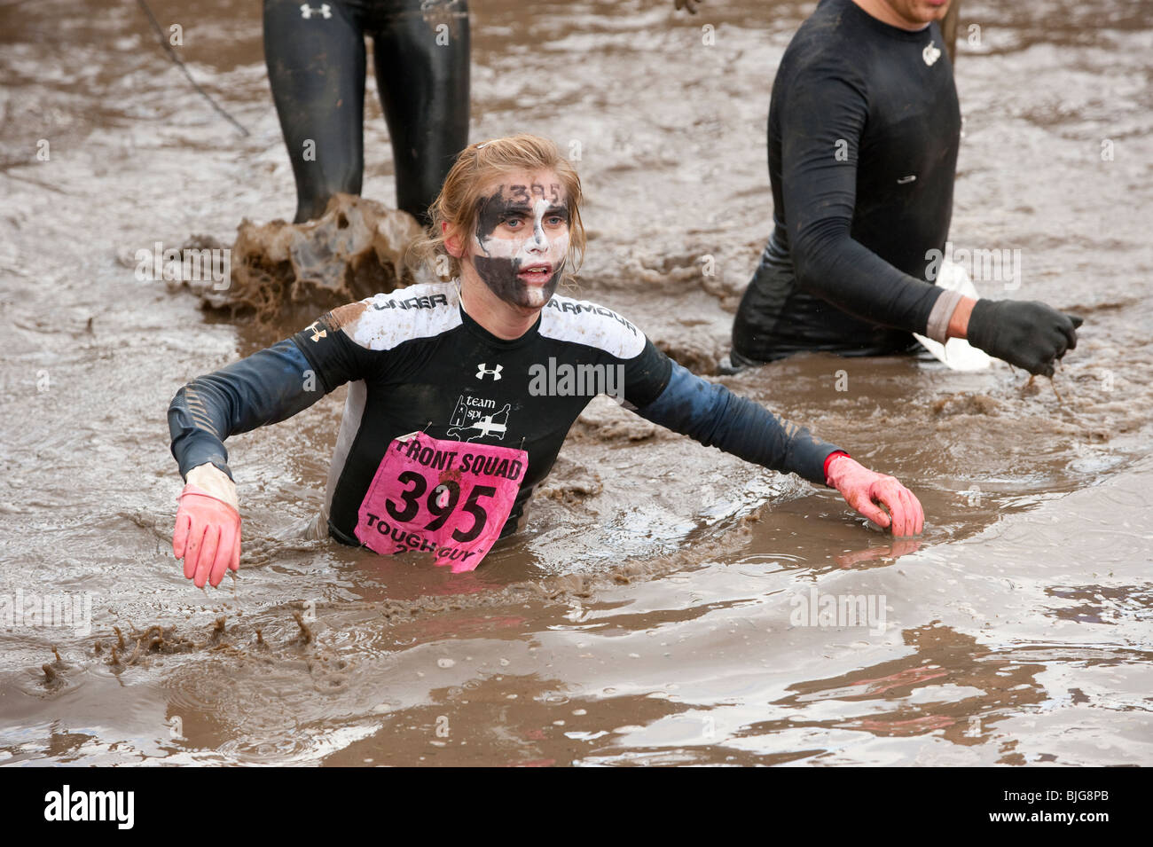 Young female cross country runner wading chest deep in cold muddy water ...