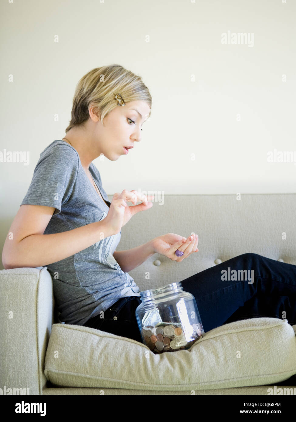 woman sitting on couch with a jar of coins Stock Photo - Alamy