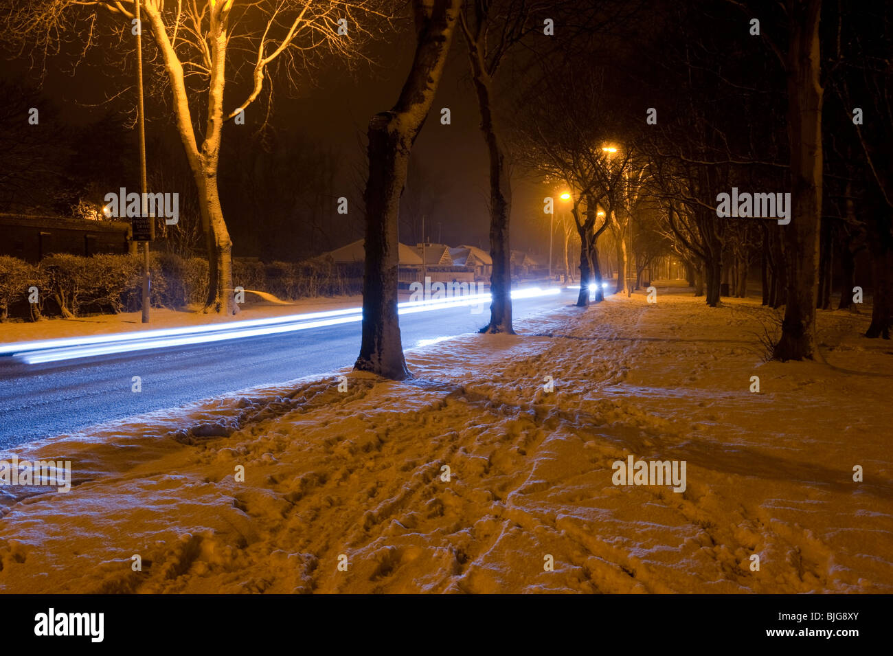 Rural road in deep snow at night with car headlight trails Stock Photo ...
