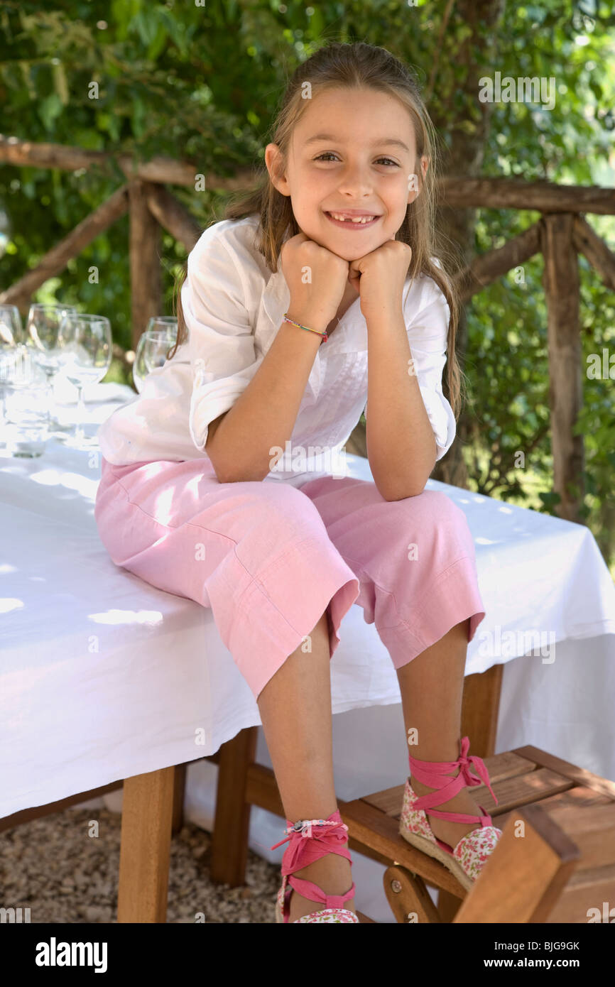 Portrait of young girl sitting on table Stock Photo - Alamy