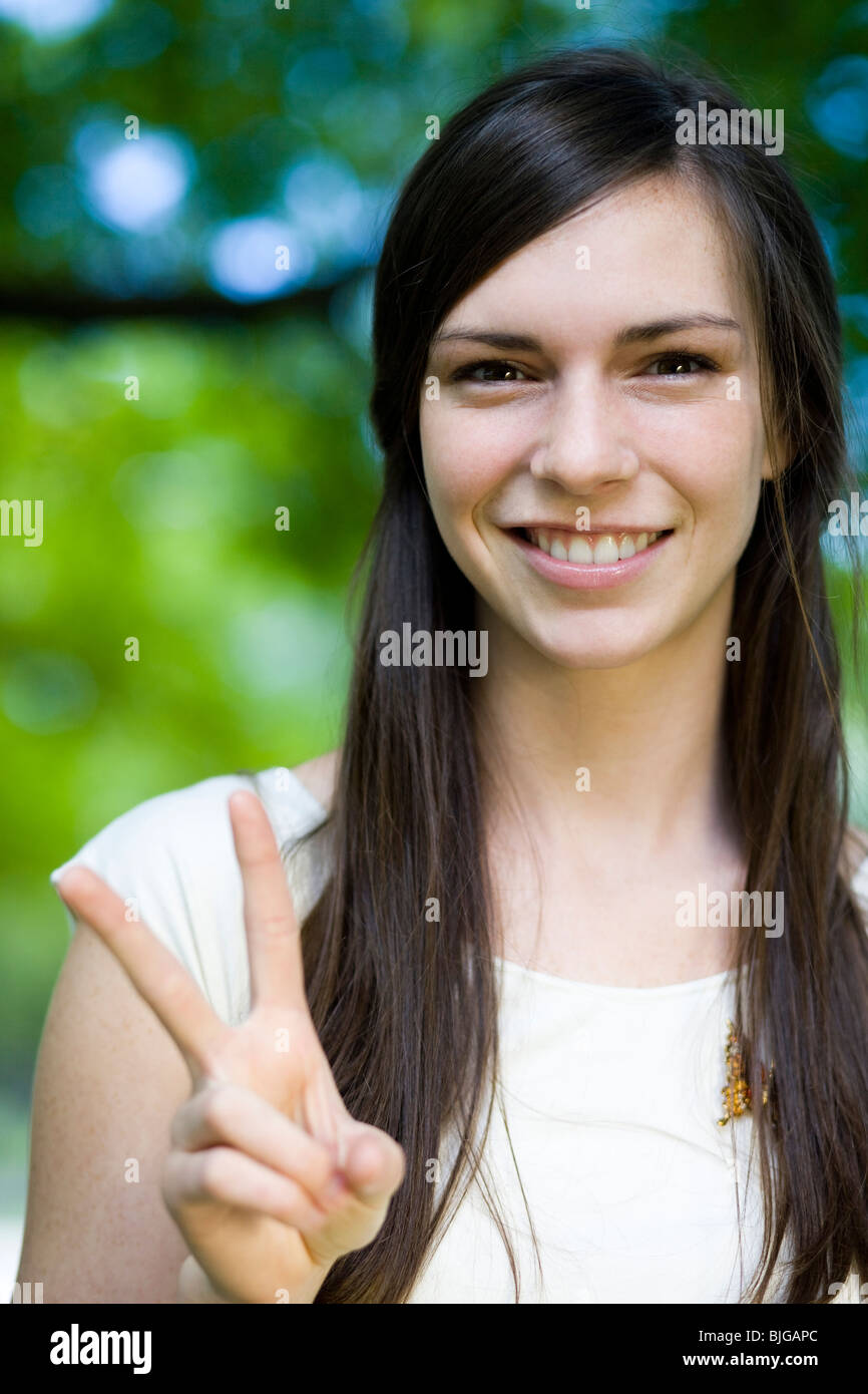 woman in a white shirt making the peace sign Stock Photo - Alamy