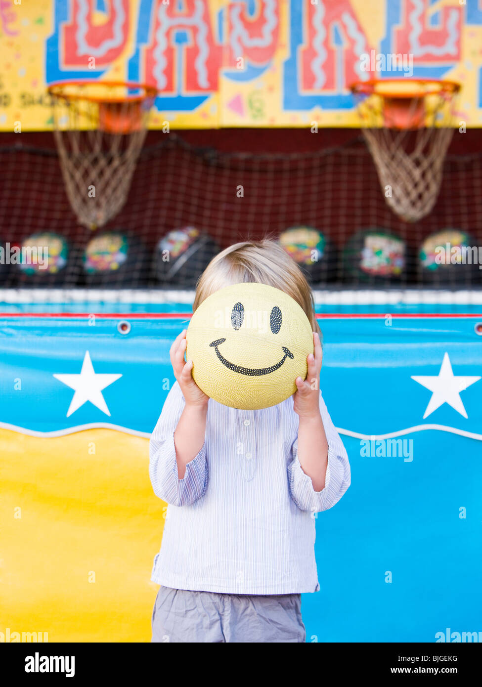 little boy holding up a smiley face at a carnival Stock Photo - Alamy