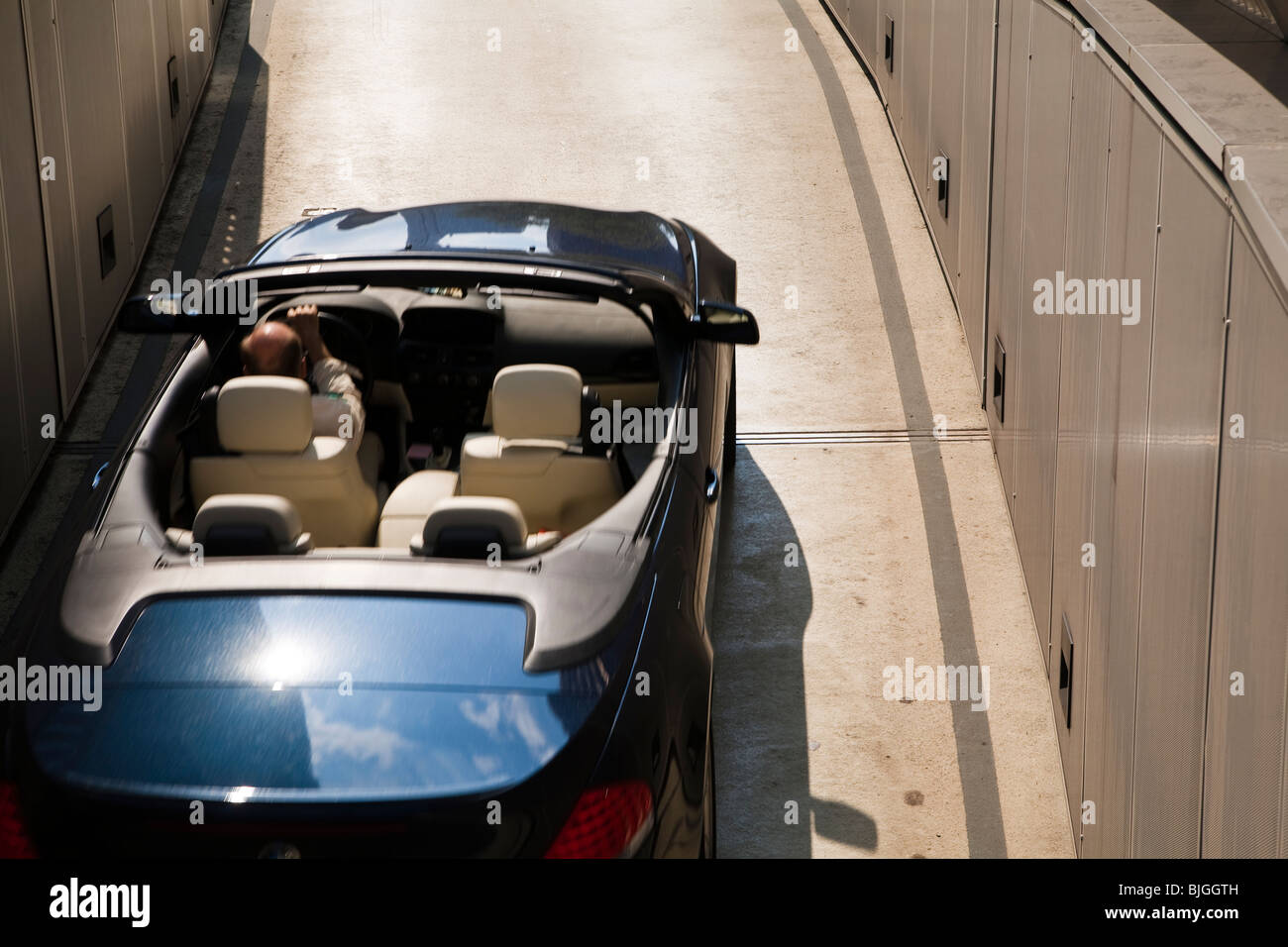 Convertible car BMW driving out of underground parking garage rear ...
