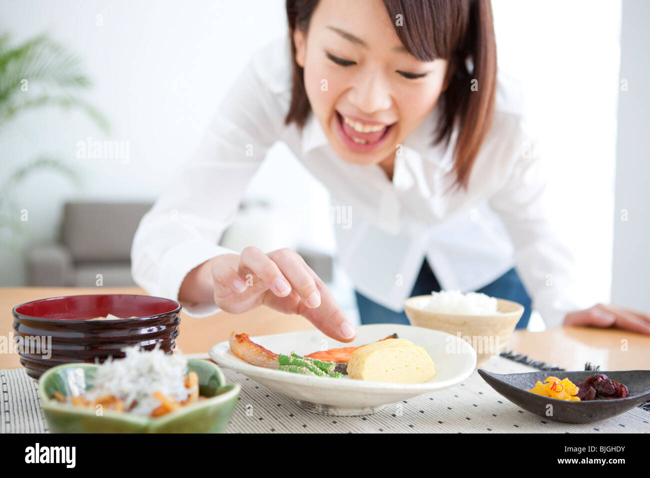 Young woman sneaking a piece of food Stock Photo - Alamy