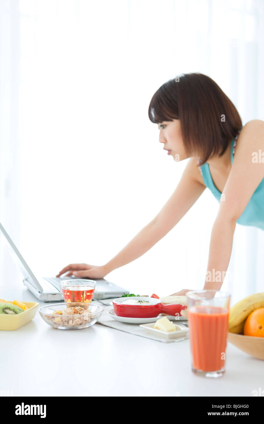 Young woman using her laptop at breakfast time Stock Photo - Alamy