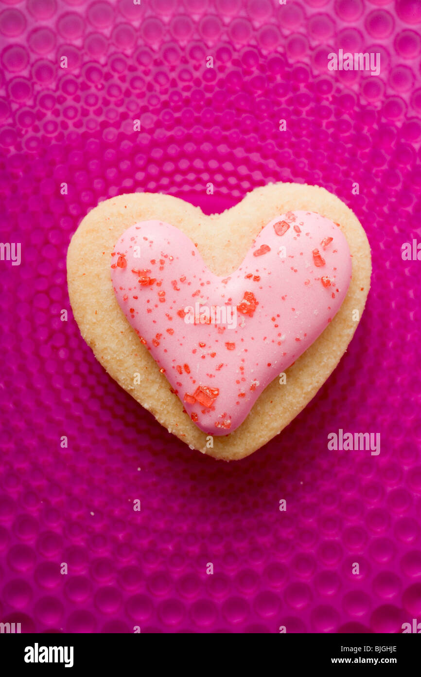 Heart-shaped biscuit with pink icing Stock Photo - Alamy