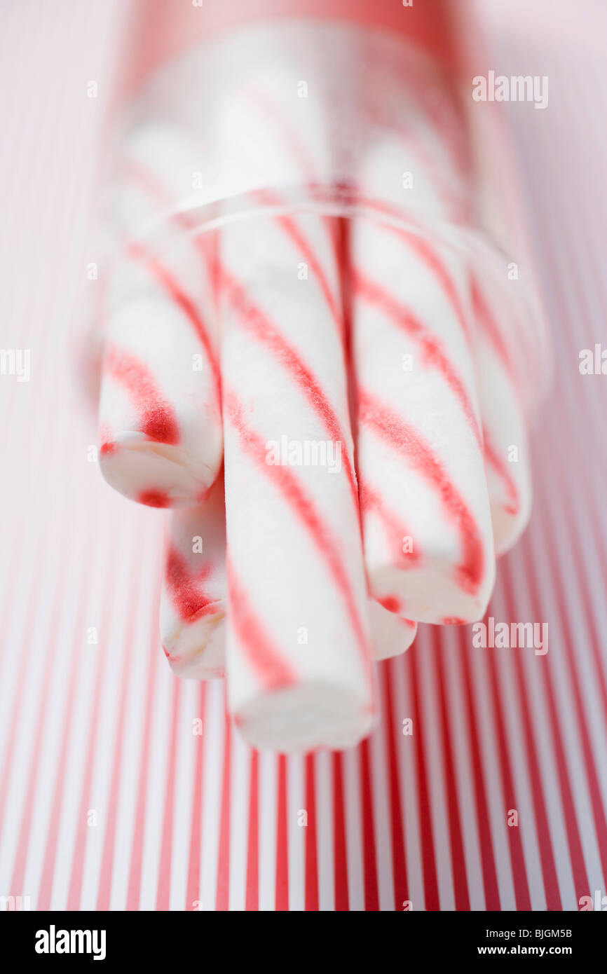 Candy canes in container on striped background Stock Photo - Alamy