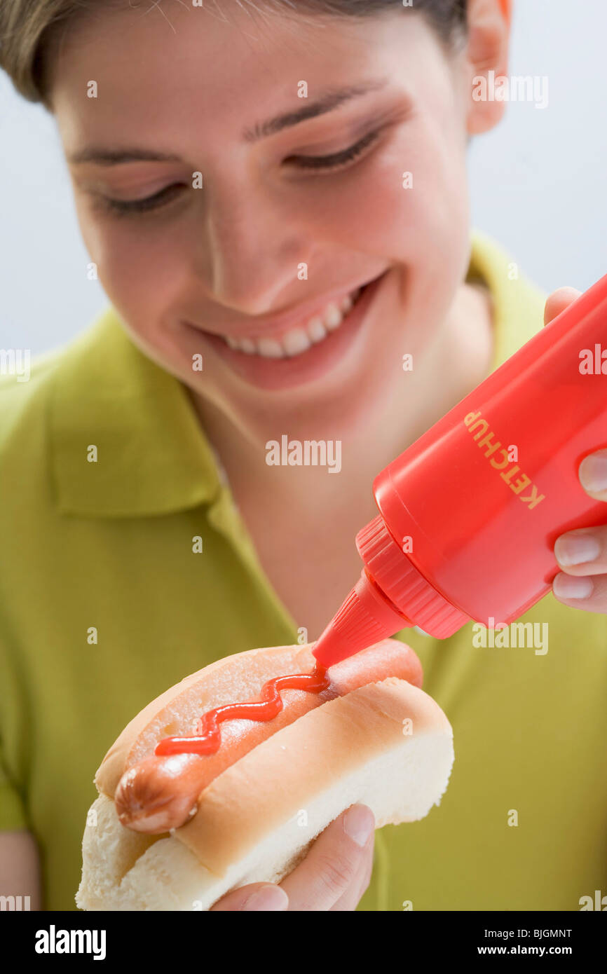 Young woman putting ketchup on hot dog Stock Photo - Alamy