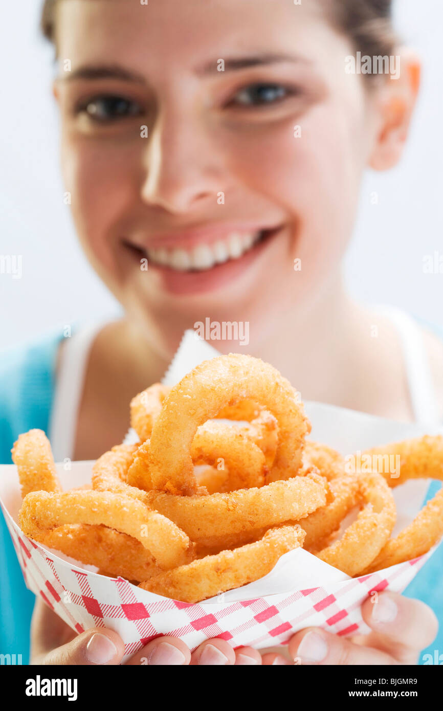 Young woman holding deep-fried onion rings in paper dish Stock Photo ...